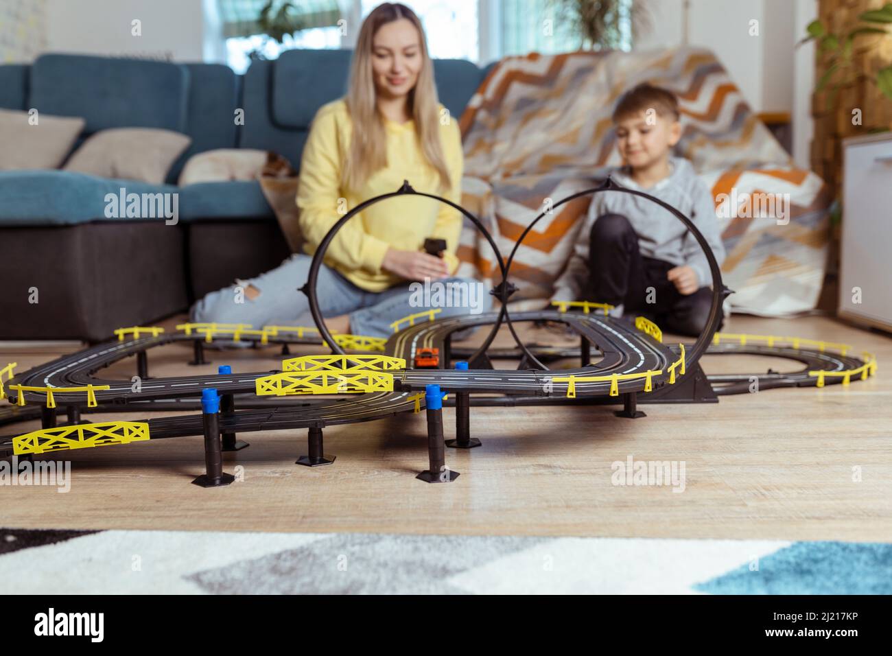 Mama und kleiner Sohn spielen zu Hause auf dem Teppich Rennen, haben ...