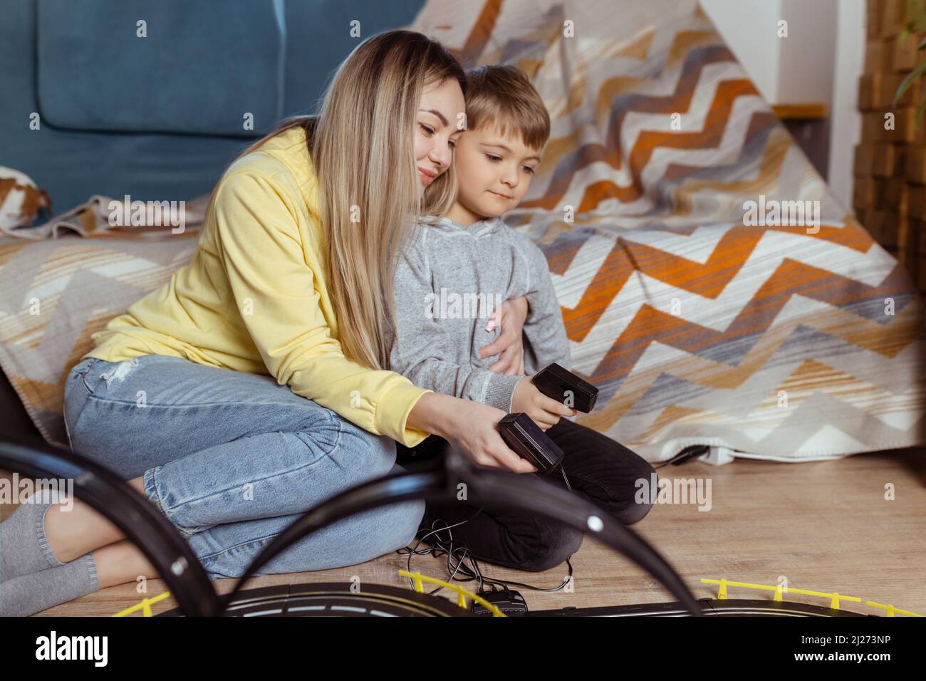 Mama und kleiner Sohn spielen zu Hause auf dem Teppich Rennen, haben ...