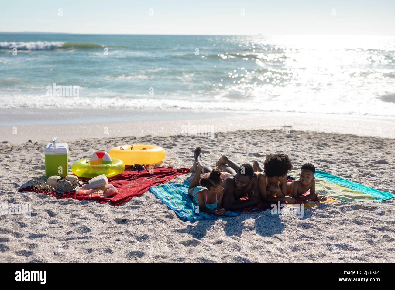 Glückliche afroamerikanische Familie, die zusammen am Strand liegt und ...