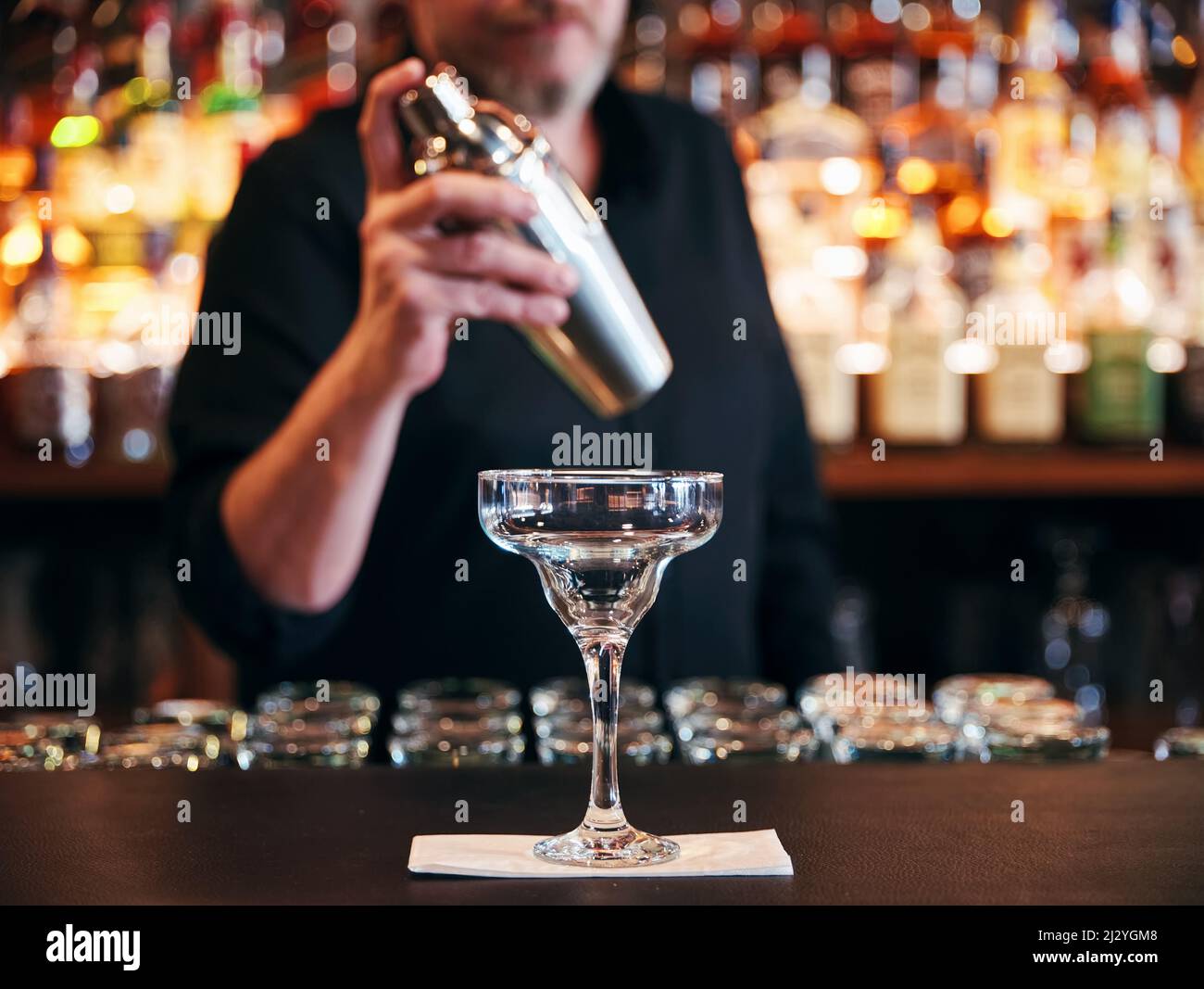 Der Barkeeper macht einen Cocktail mit einem Shaker hinter der Theke im ...