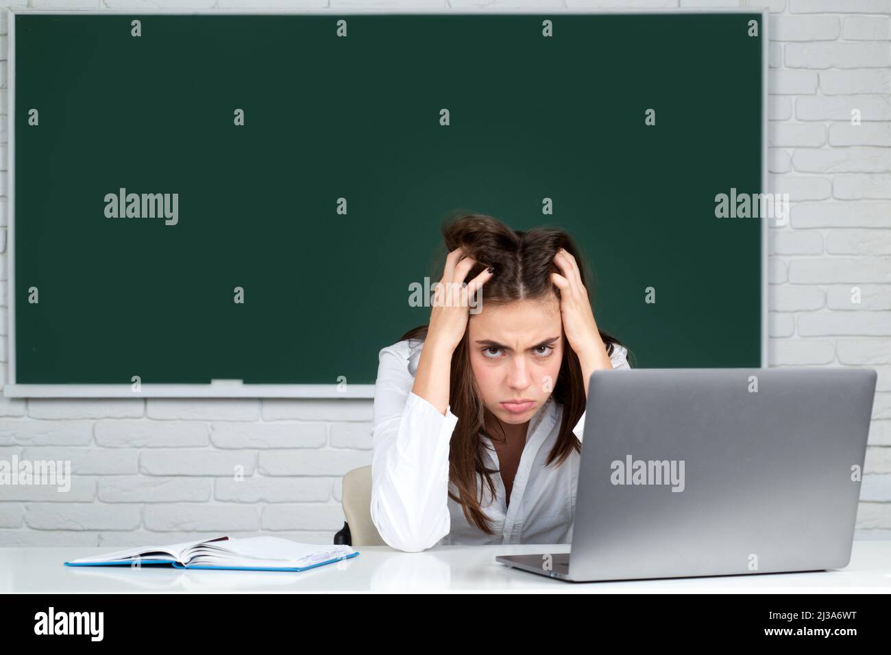 Traurige und verärgerte Schüler, die im Klassenzimmer einen Computer ...