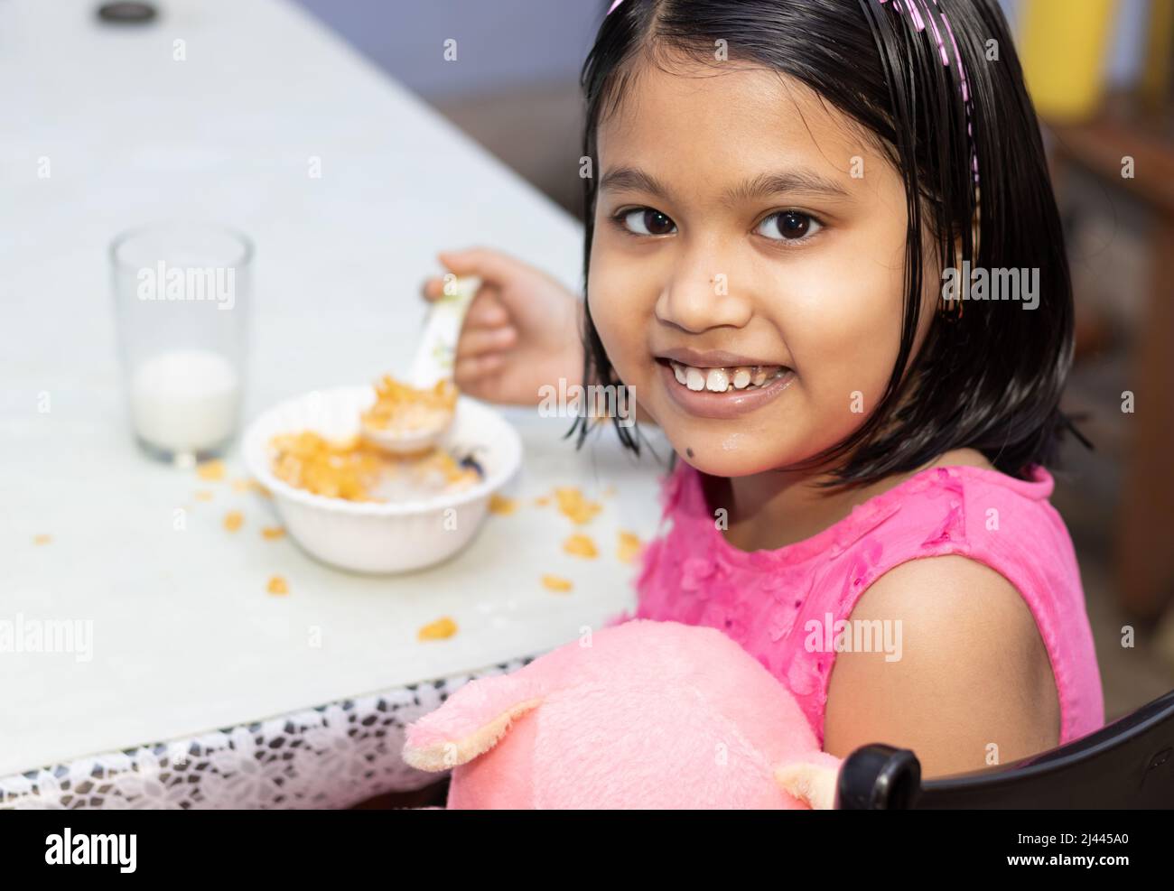 Ein indisches Mädchen, das Getreide und Milch mit lächelndem Gesicht ...