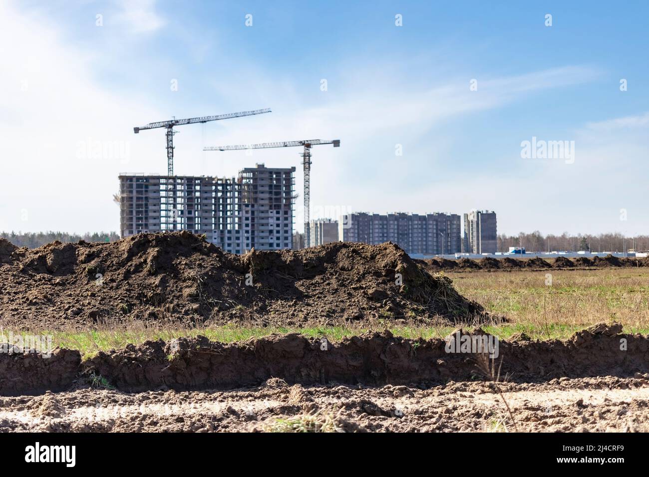 Ein Erdhaufen, der aus einem Graben gegen einen blau bewölkten Himmel ...