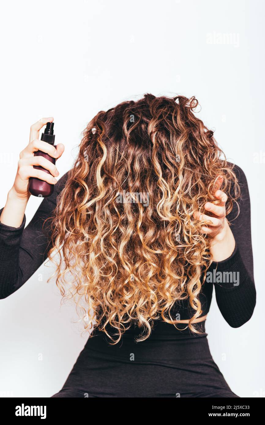 Der Kopf der jungen Frau mit langen lockigen Haaren wird gesenkt, um ...