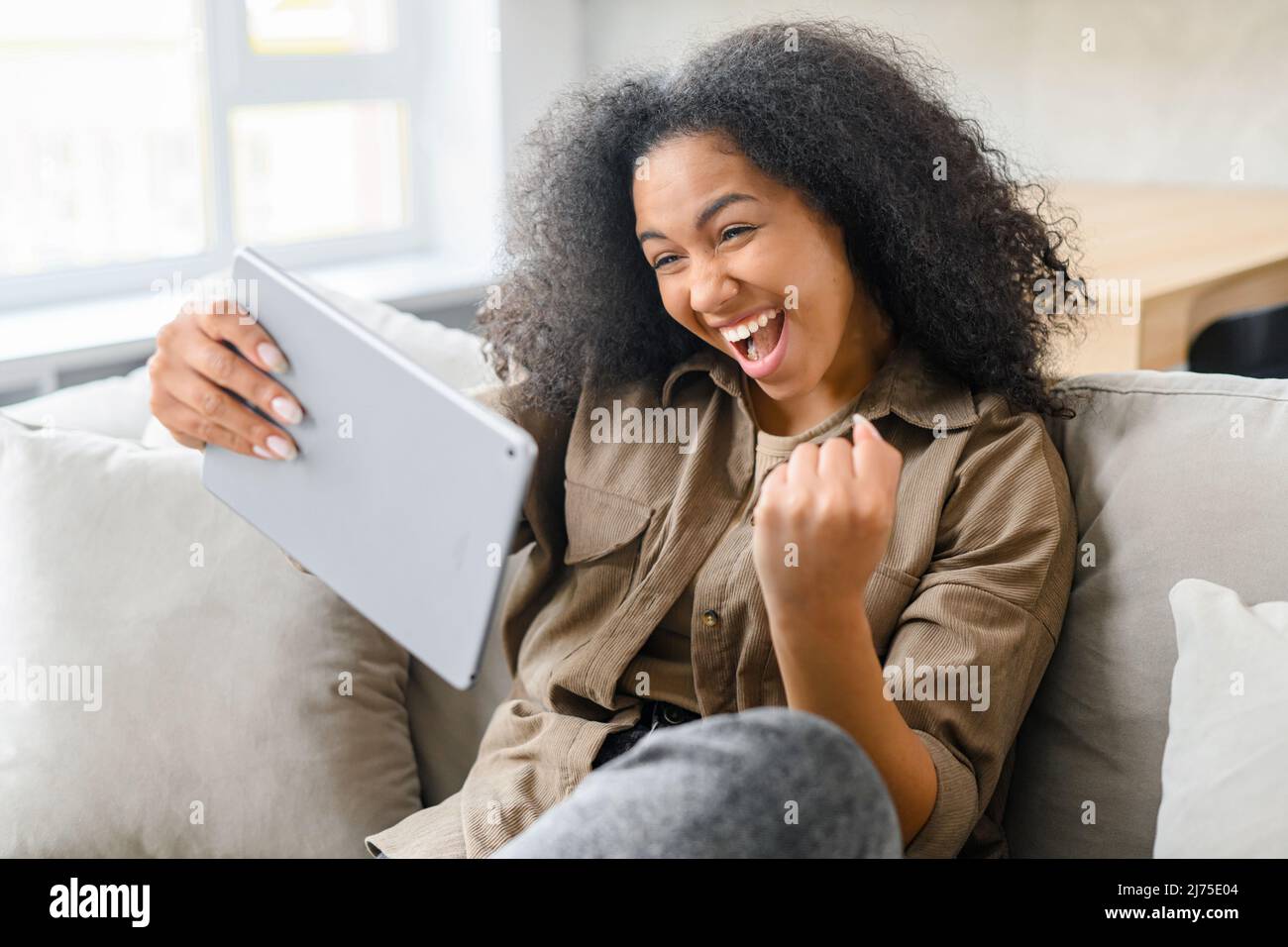 Überglücklich, wenn die Frau auf den Tablet-Bildschirm schaut und den Erfolg feiert. Aufgeregt ...