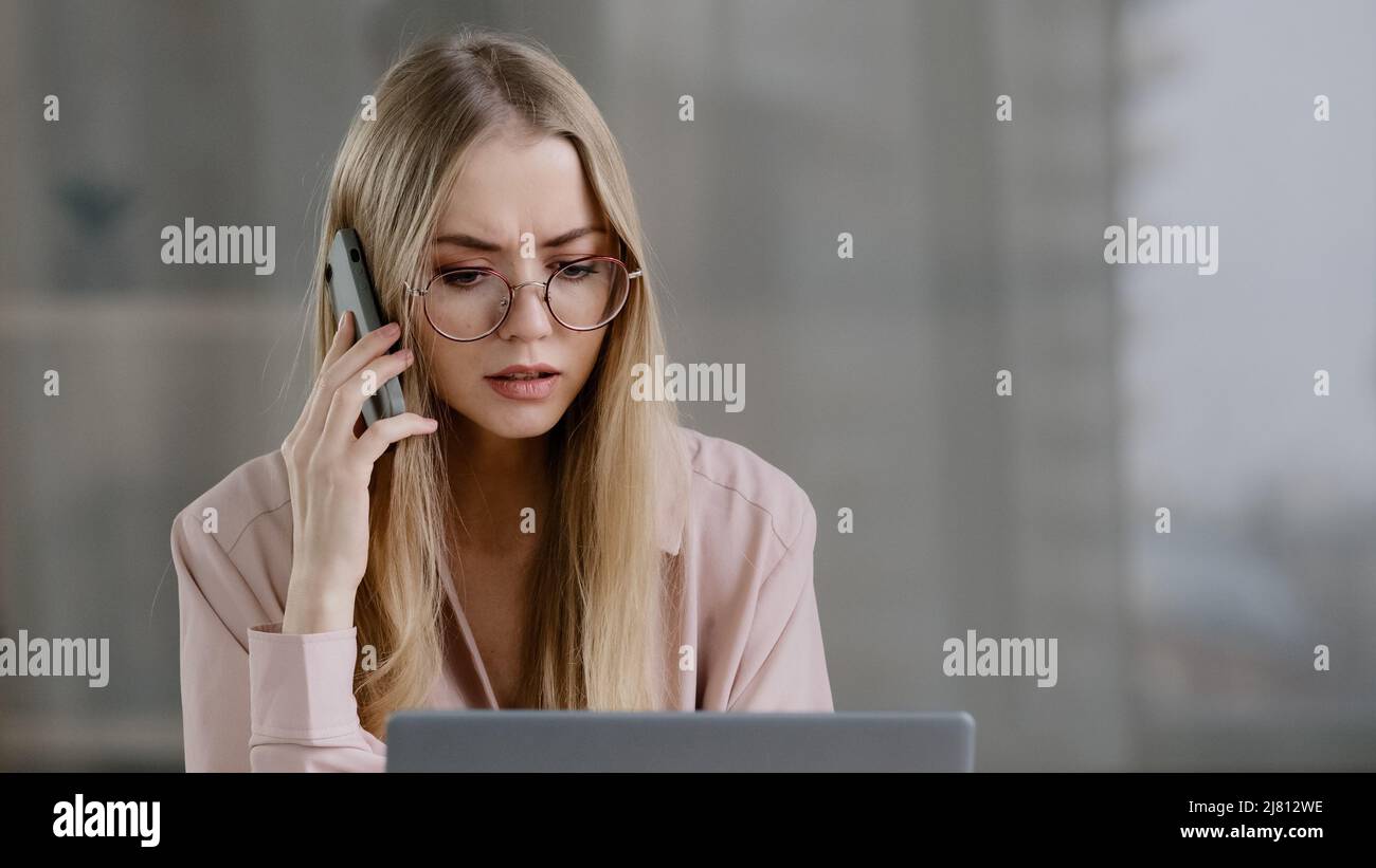 Verärgerte kaukasische Frau telefonieren am Arbeitsplatz im Büro ... Verärgerte kaukasische Frau telefonieren am Arbeitsplatz im Büro ...