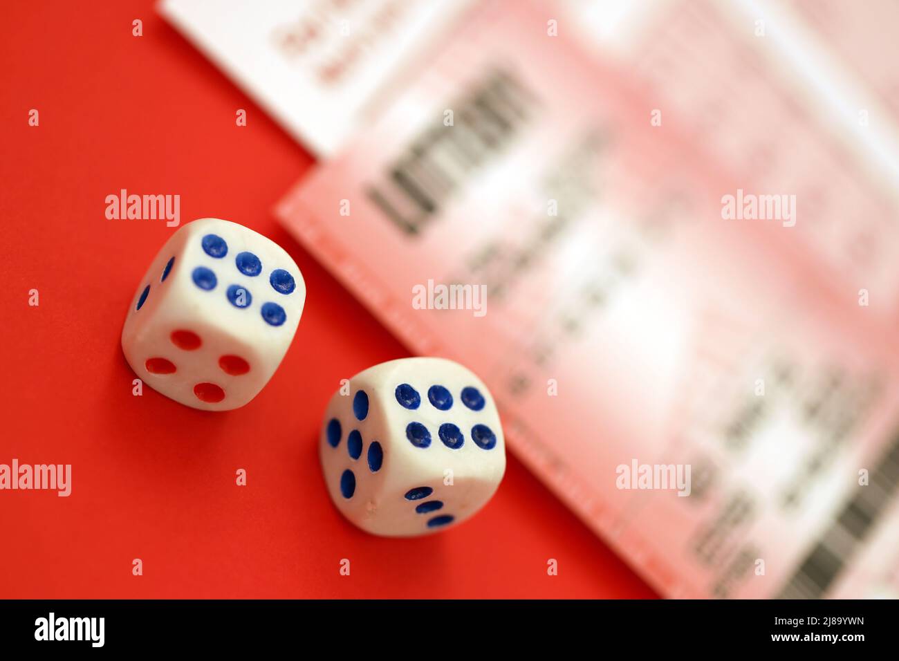 Rote Lotterie-Ticket mit Würfel liegt auf rosa Glücksspiel-Blätter mit ...