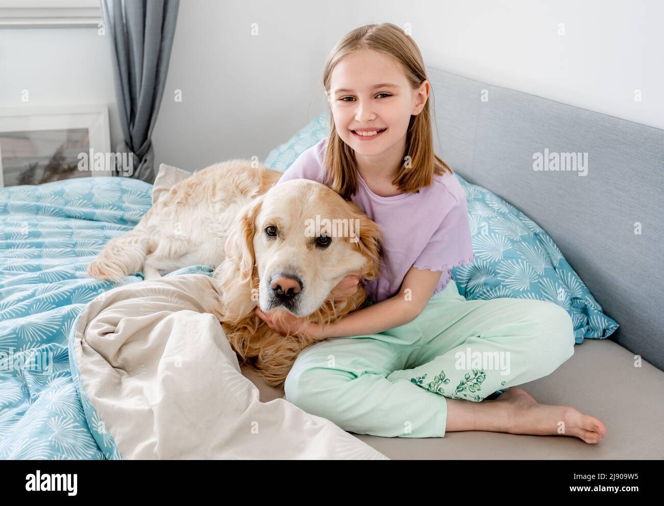 Das kleine Mädchen umarmte den goldenen Retriever-Hund, der morgens im ...