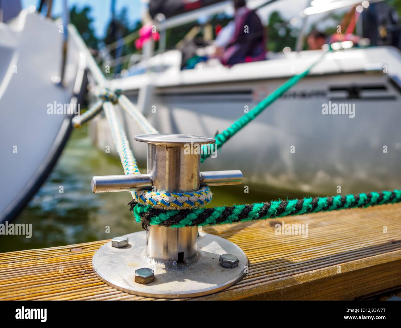 Ein weißes Segelboot, das mit einer um eine Metallbefestigung ...
