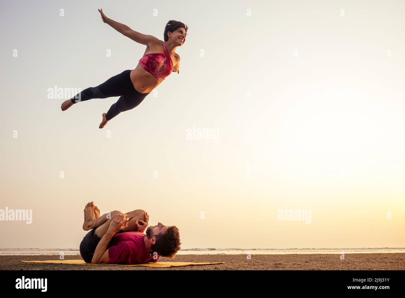 Zwei Menschen praktizieren Yoga im Abendlicht am strand von goa india ...