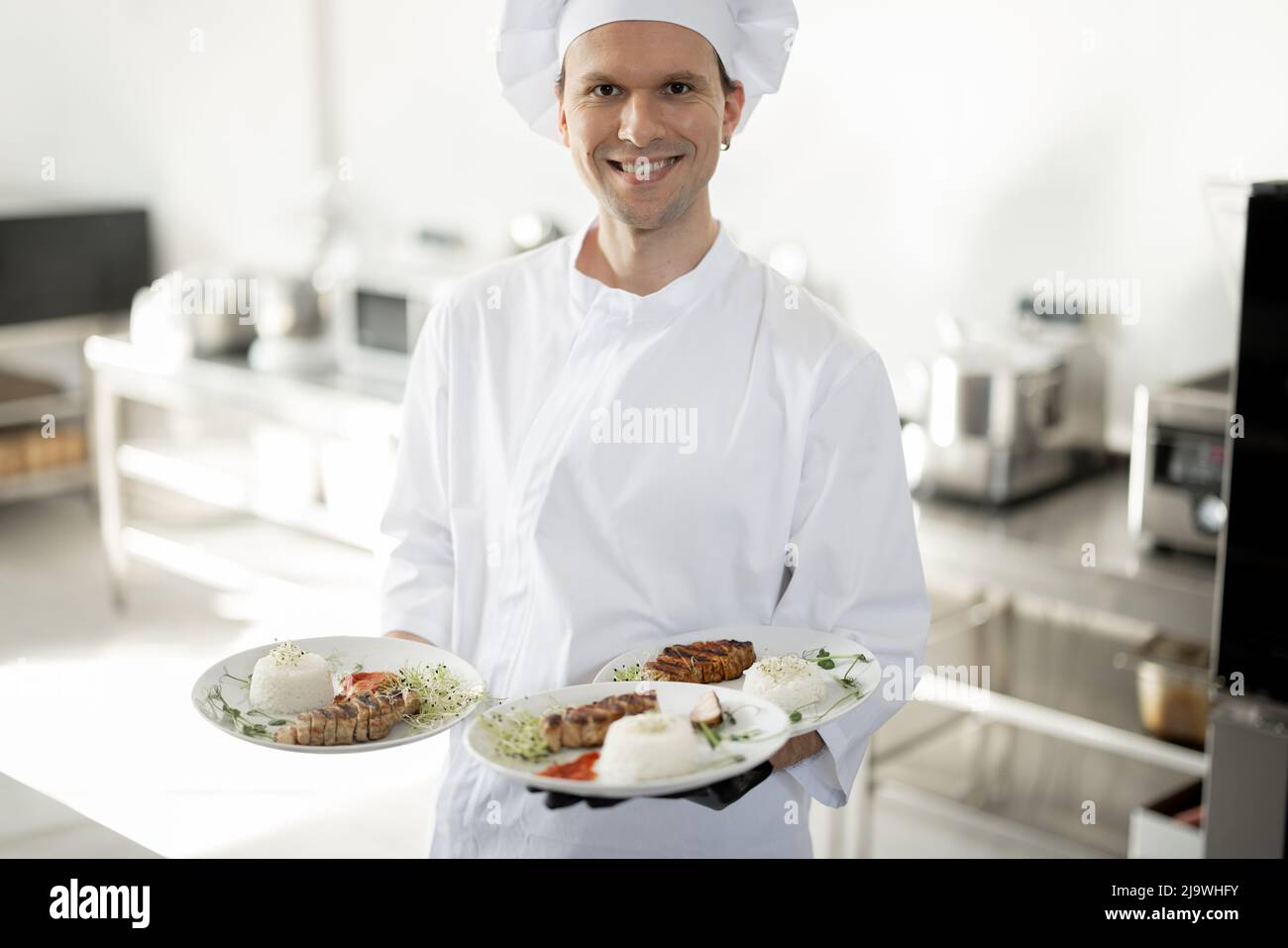 Porträt eines jungen, gutaussehenden, lächelnden Küchenchefs in Uniform ... Porträt eines jungen, gutaussehenden, lächelnden Küchenchefs in Uniform ...
