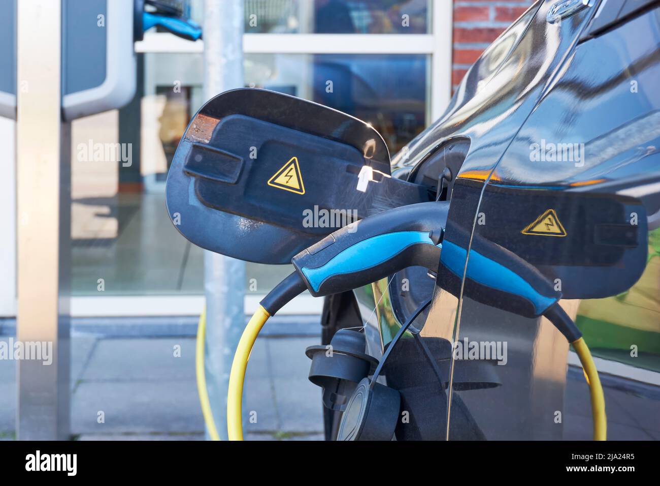 Elektroauto mit blauem Stecker und gelbem Kabel, das an einer ...