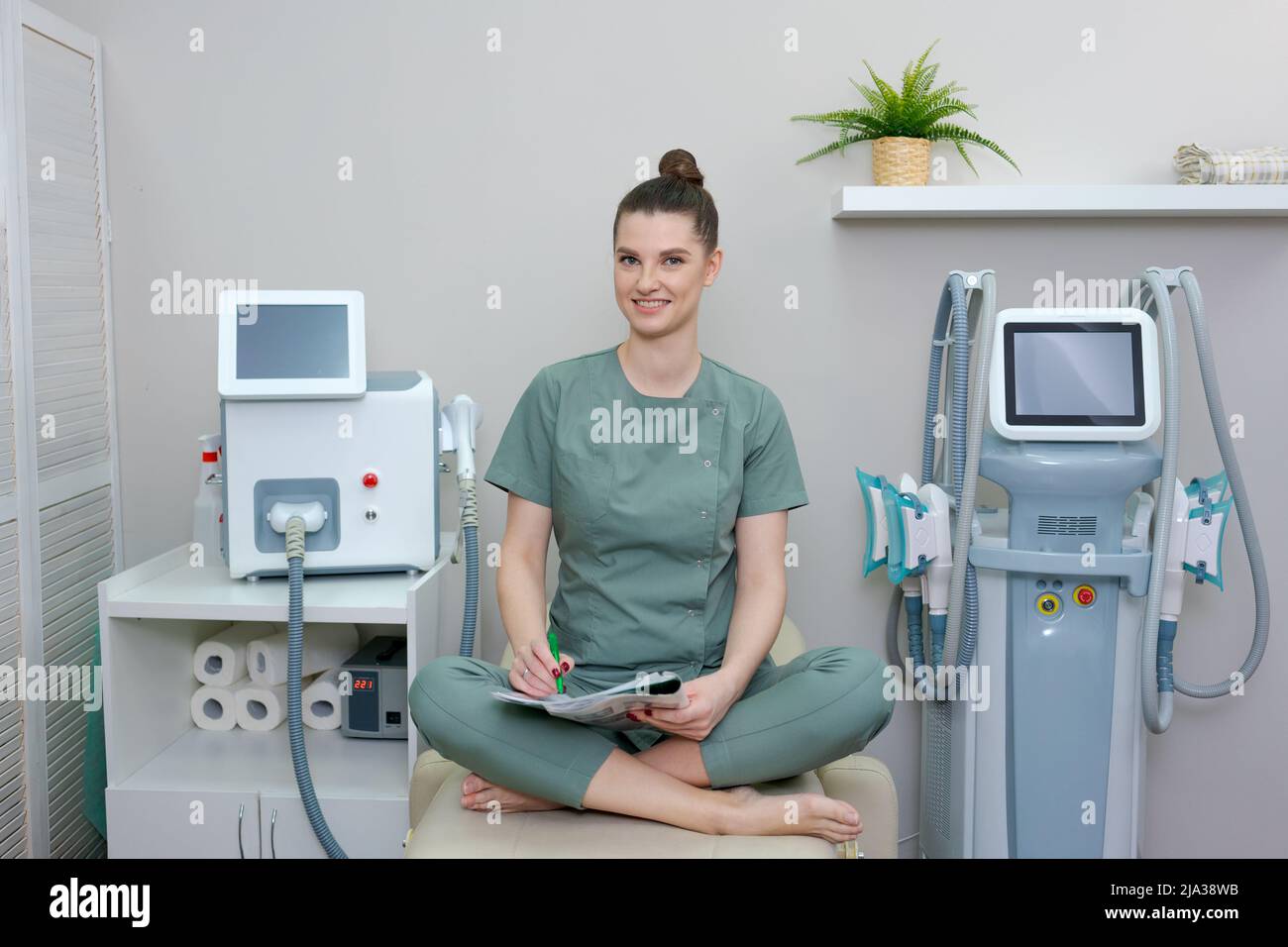 Der Kosmetologe steht an der Laser-Haarentfernungsmaschine mit Ordner ...