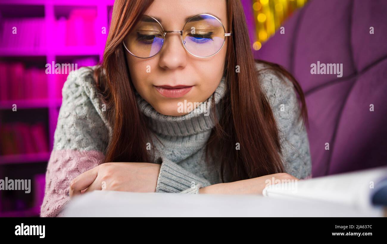 Eine schöne Schülerin mit Brille, die ein großes Buch liest. Eine ...
