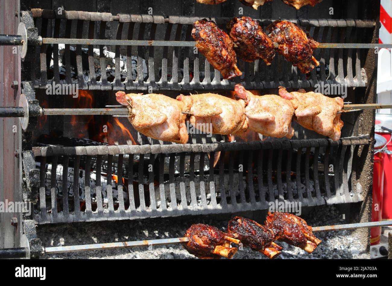 Industrielle Rotisserie mit Spieß-gebratenen Hühnern und Schweinshank ...