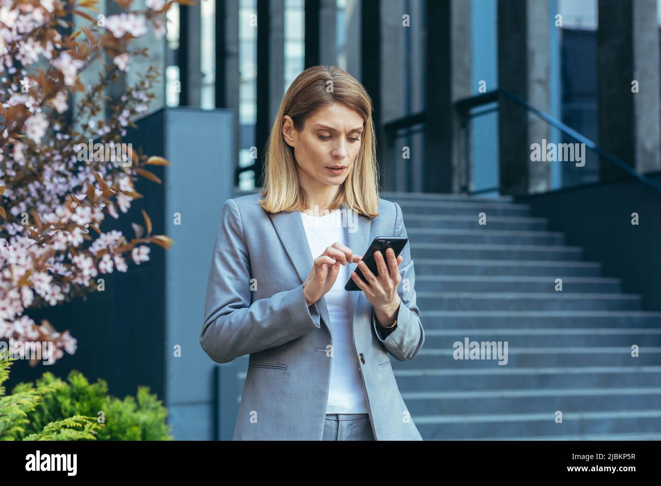Seriöse und nachdenkliche Geschäftsfrau nutzt das Telefon außerhalb des ...
