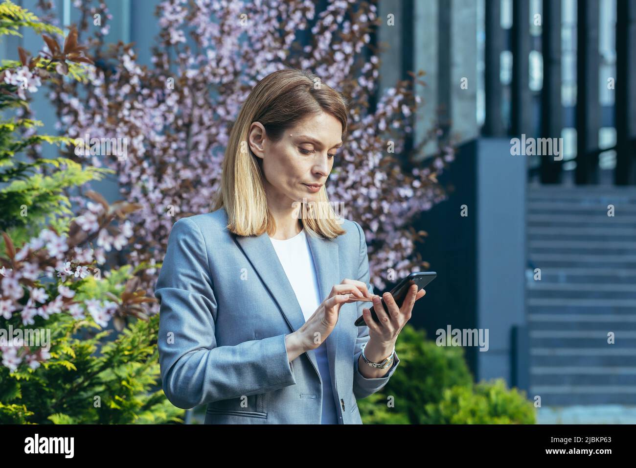 Seriöse und nachdenkliche Geschäftsfrau nutzt das Telefon außerhalb des ...
