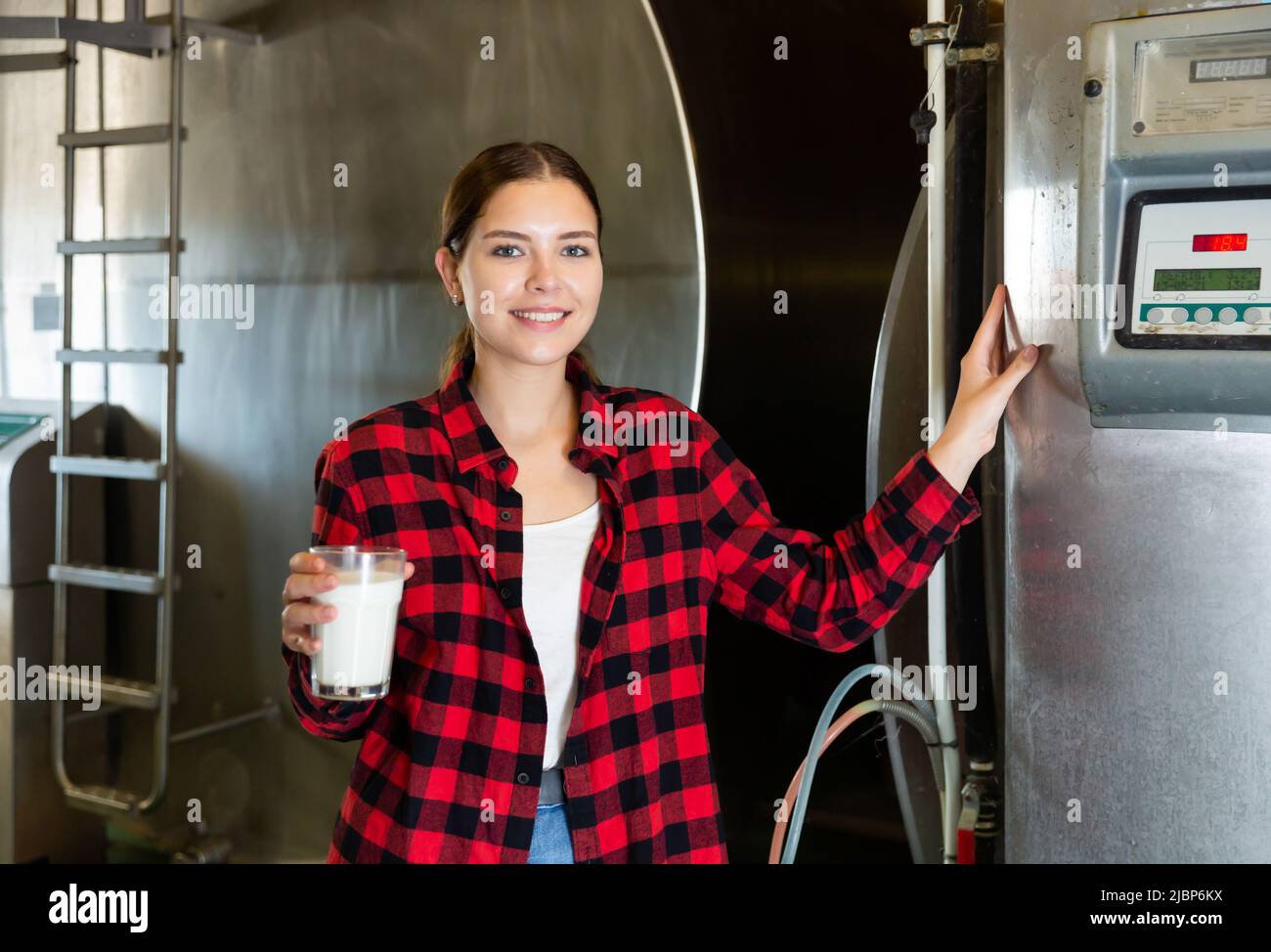 Melkerin posiert mit einem Glas Milch auf einem Milchviehbetrieb ...