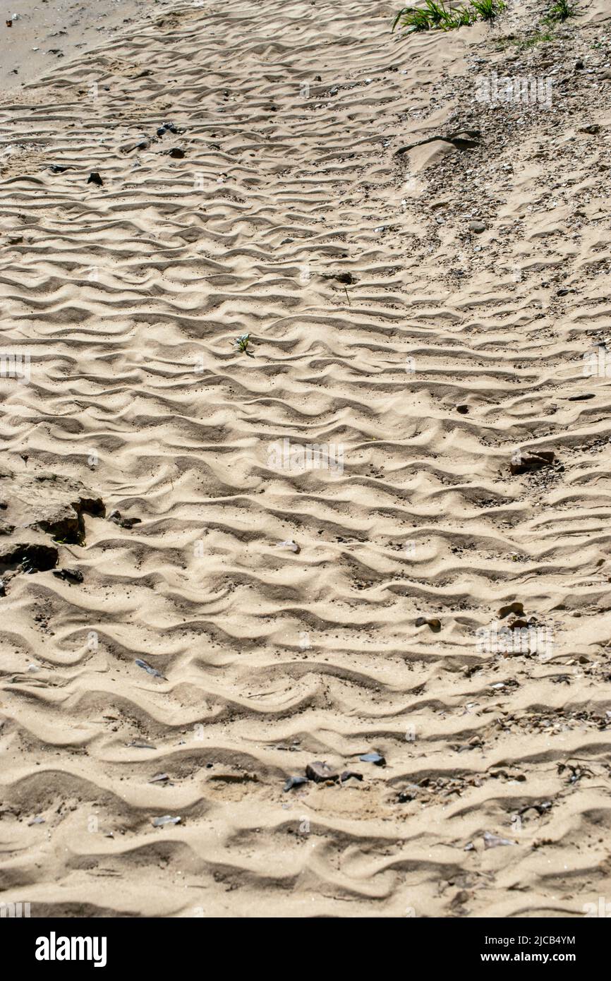 Sand am Flussufer ähnelt Wellen im Wasser. Dreck, Schutt und Kies haben ...
