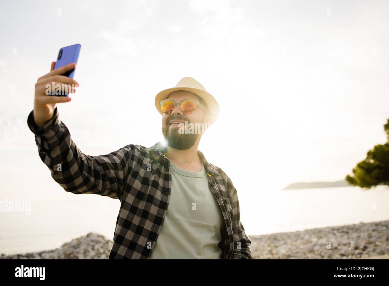 Reisende oder Touristen fotografieren sich mit dem Smartphone am Meer ...