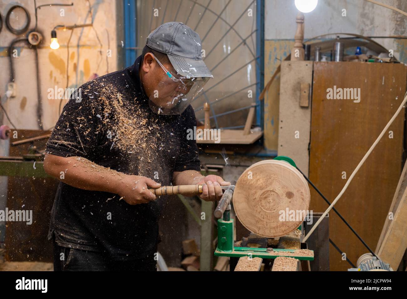 Zimmermann dreht Holz auf einer Drehbank in der Werkstatt. Person, die ...