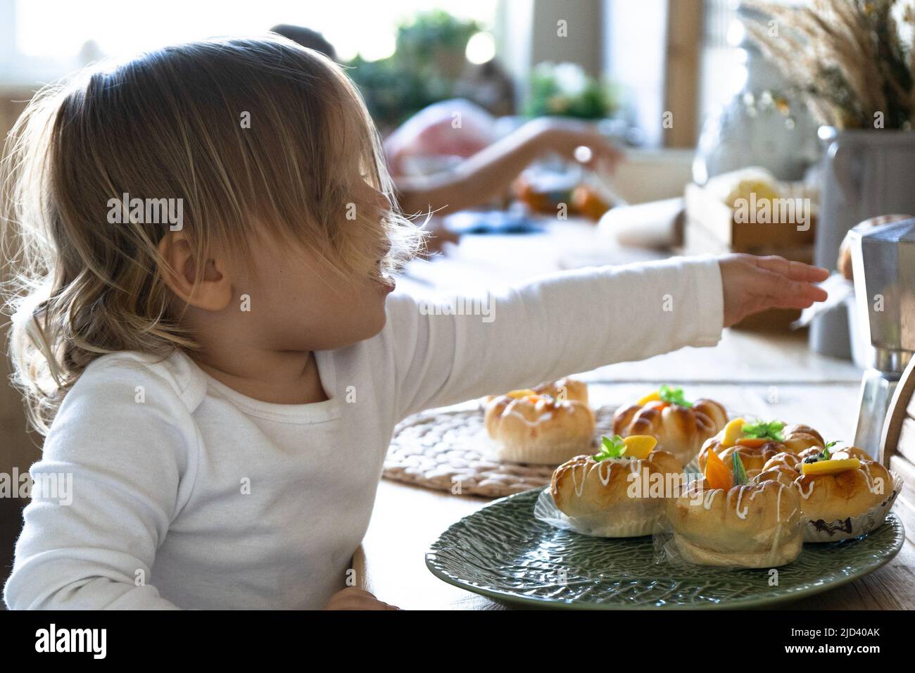 Das Baby sieht frische Kuchen mit Neugier .Kinder Unabhängigkeit und ...