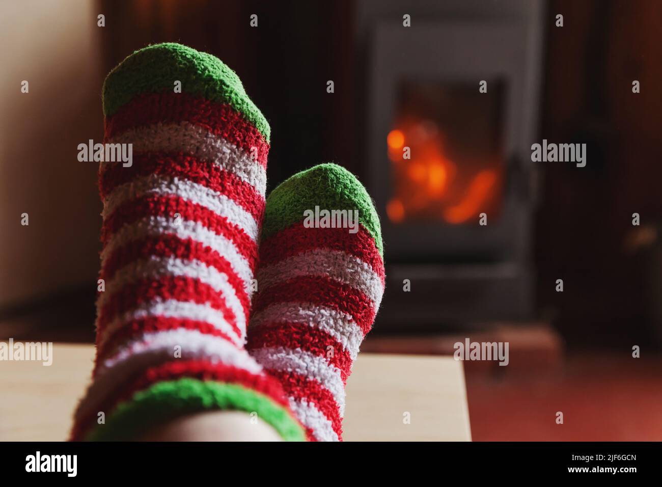 Füße Beine im Winter Kleidung Wolle Socken am Kamin Hintergrund. Frau ...