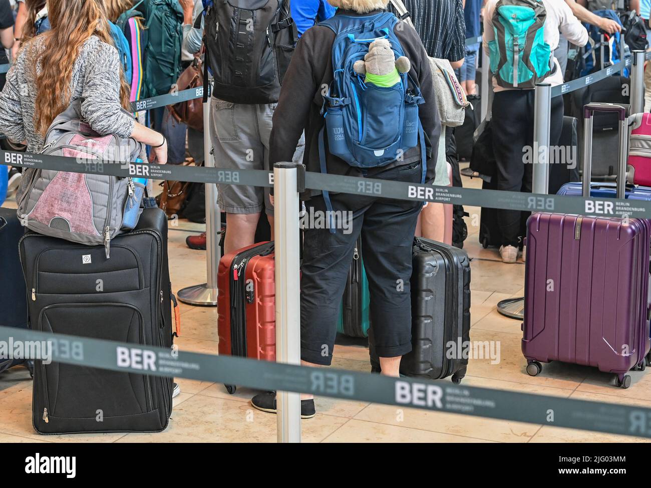 06. Juli 2022, Brandenburg, Schönefeld: Reisende warten beim Check-in ...