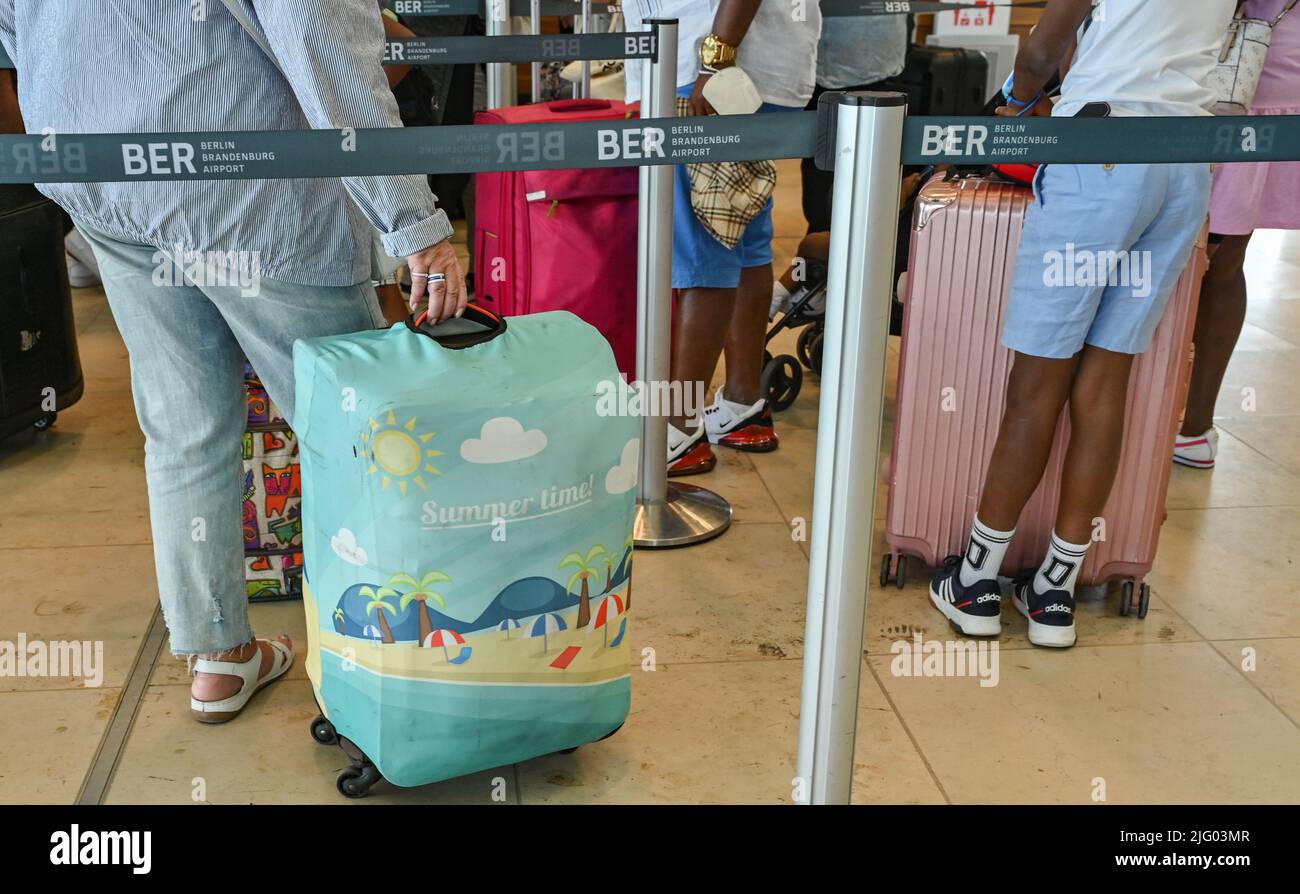 06. Juli 2022, Brandenburg, Schönefeld: Reisende warten beim Check-in ...