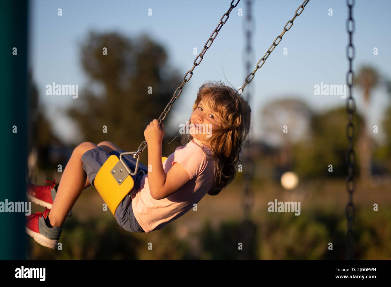 Kinder schaukeln auf dem Spielplatz. Netter kleiner Junge lustig beim ...