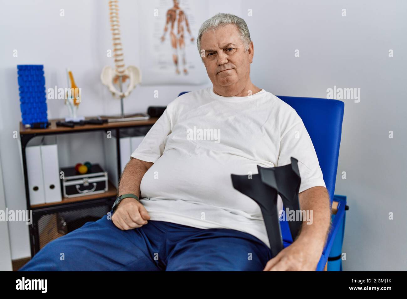 Leitender kaukasischer Mann in der Physiotherapie-Klinik, der Krücken ...
