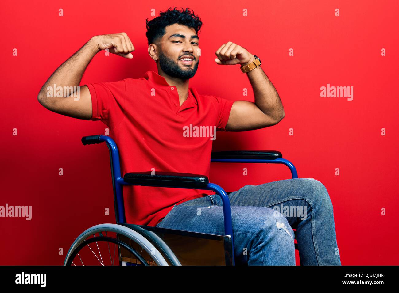 Arabischer Mann mit Bart auf dem Rollstuhl sitzend, zeigt Arme, die Muskeln lächeln stolz ...