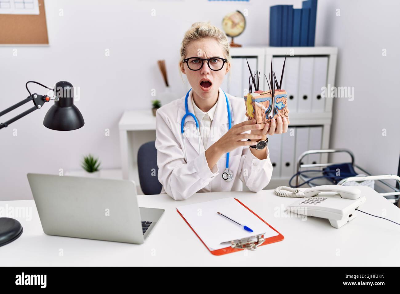 Junge Ärztin mit Modell der menschlichen anatomischen Haut und Haare in ...
