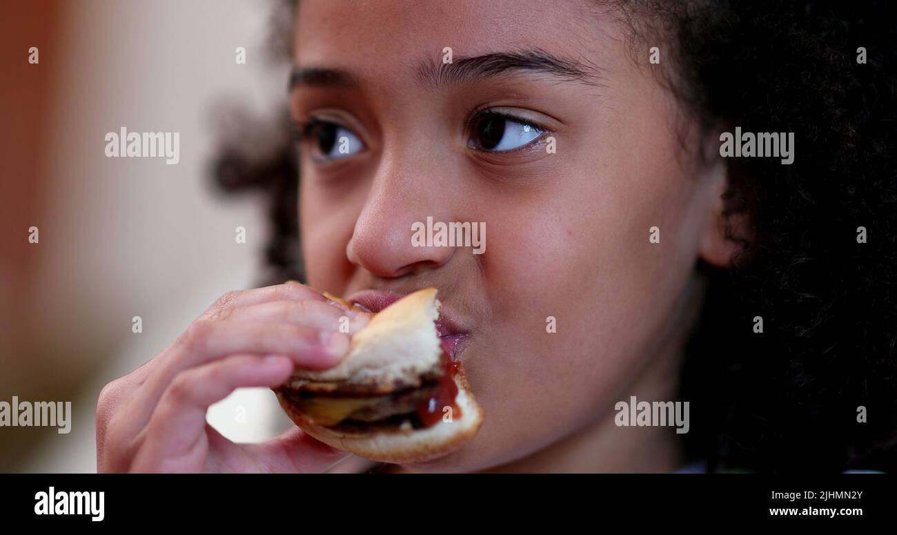 Kleines Mädchen, das Burger isst. Kind, das einen Bissen Hamburger ...