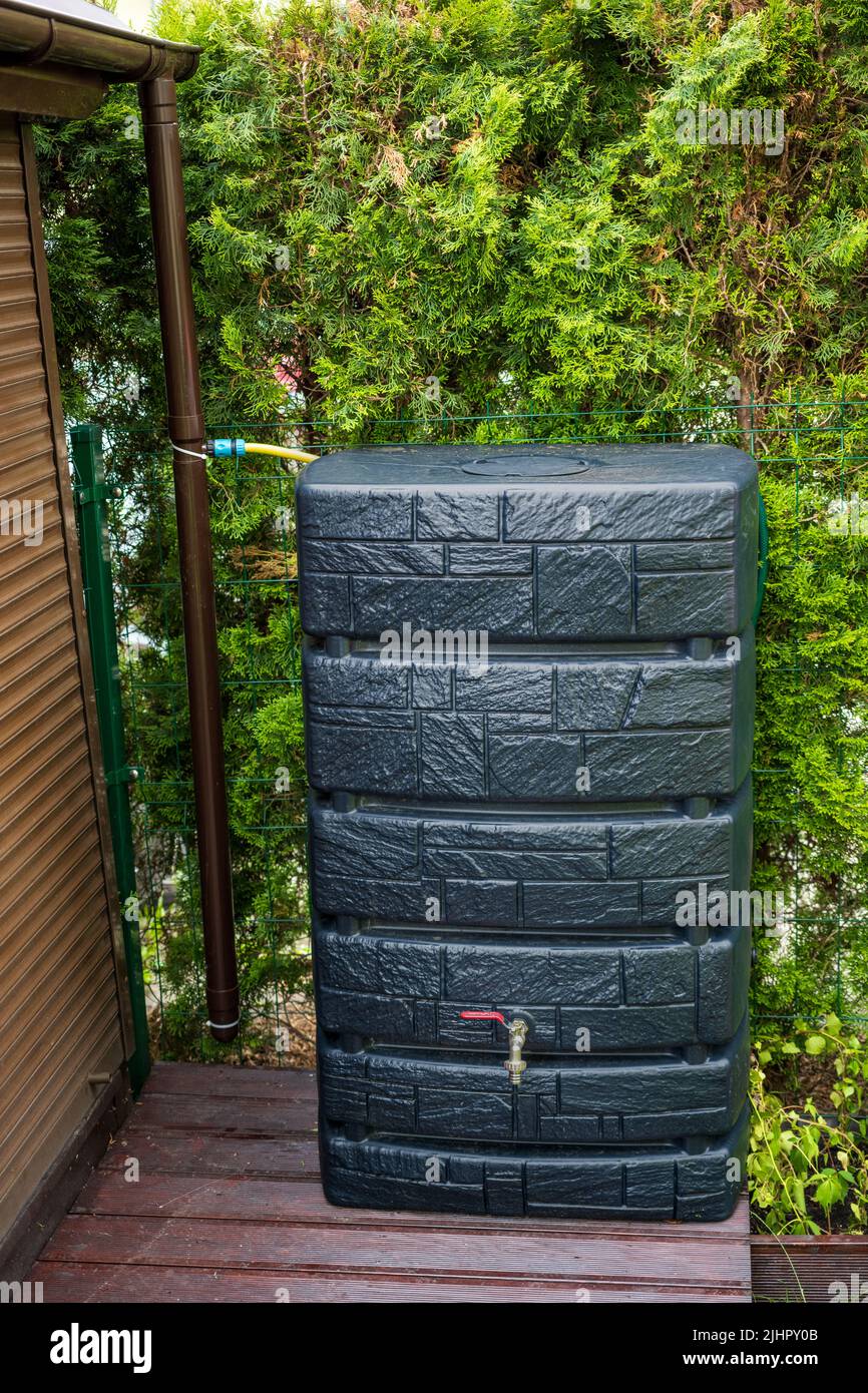 Großer Regenwassertank, der mit den Dachrinnen auf der Terrasse ...