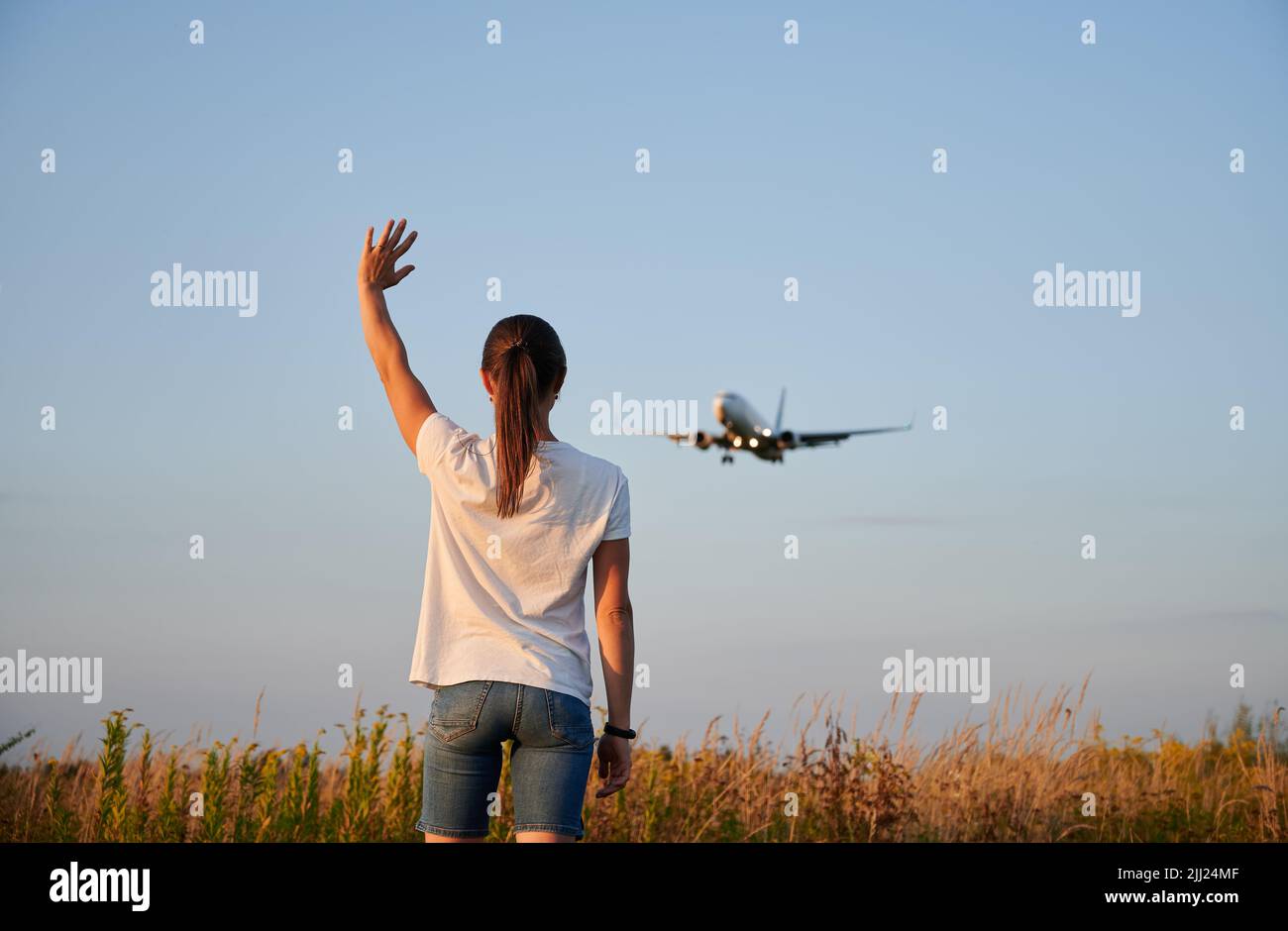 Rückansicht einer Frau, die am Abend mit der Hand zum fliegenden ...