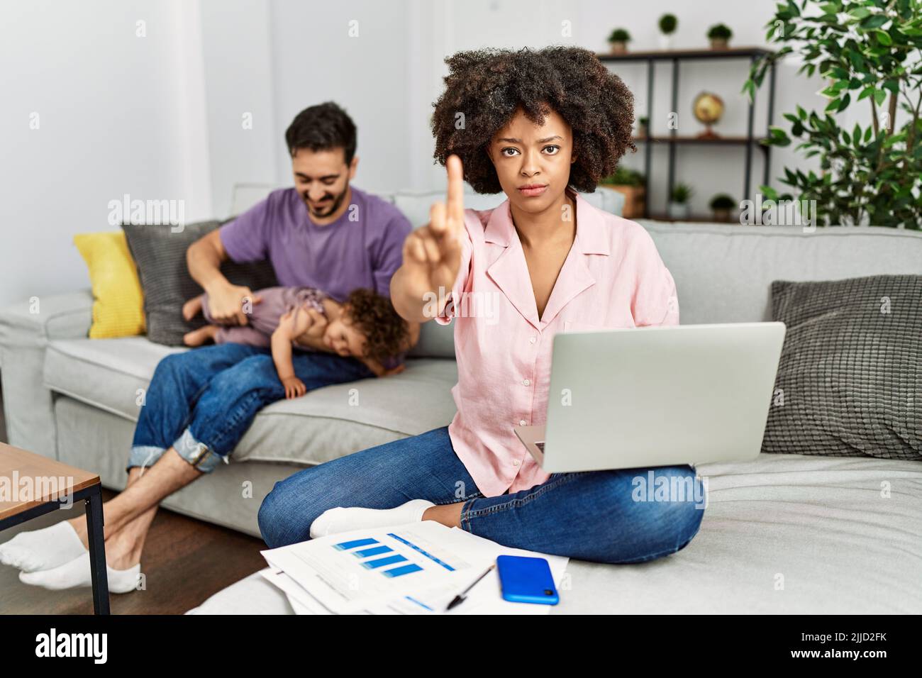 Mutter einer interrassischen Familie, die zu Hause mit einem Computer ...