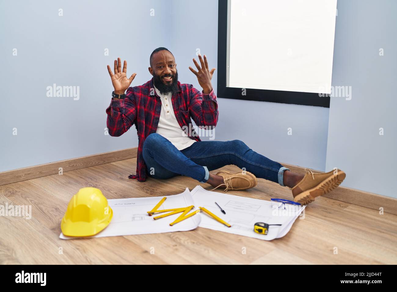 afroamerikanischer Mann, der in einem neuen Zuhause auf dem Boden sitzt ...