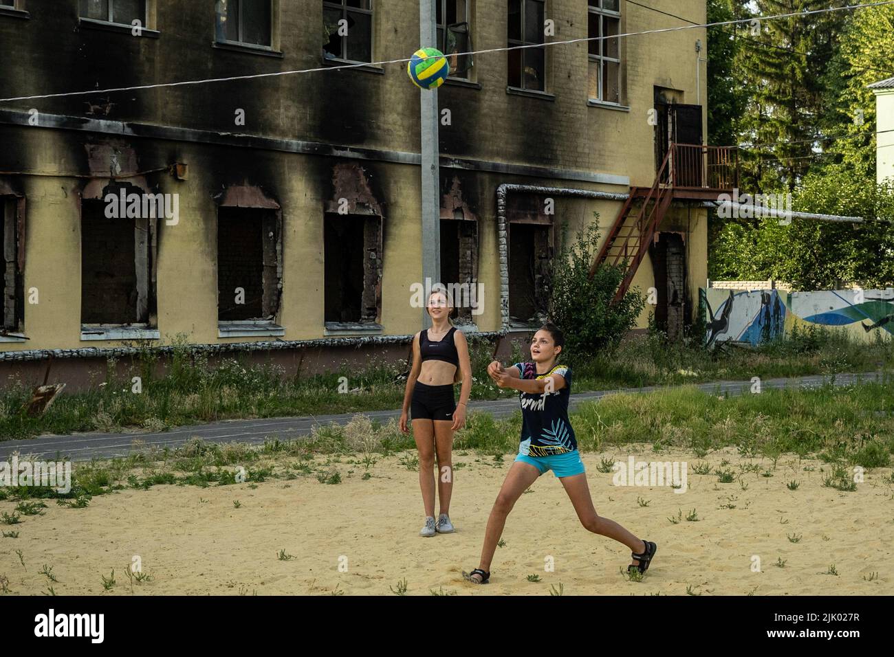 Eine Familie spielt Volleyball neben den Ruinen einer Schule in Charkiw ...