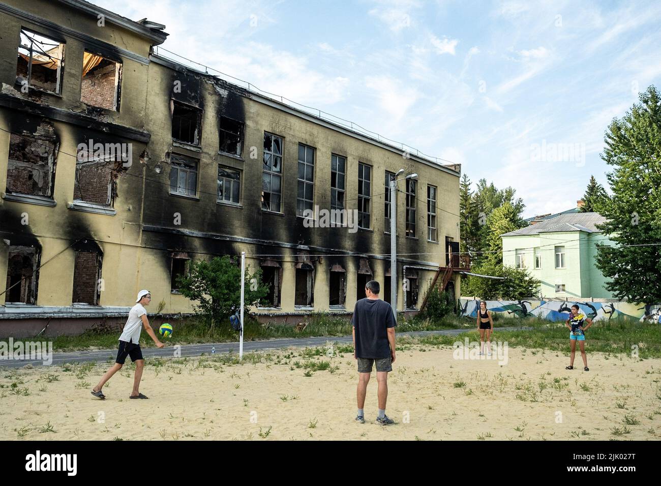Eine Familie spielt Volleyball neben den Ruinen einer Schule in Charkiw ...