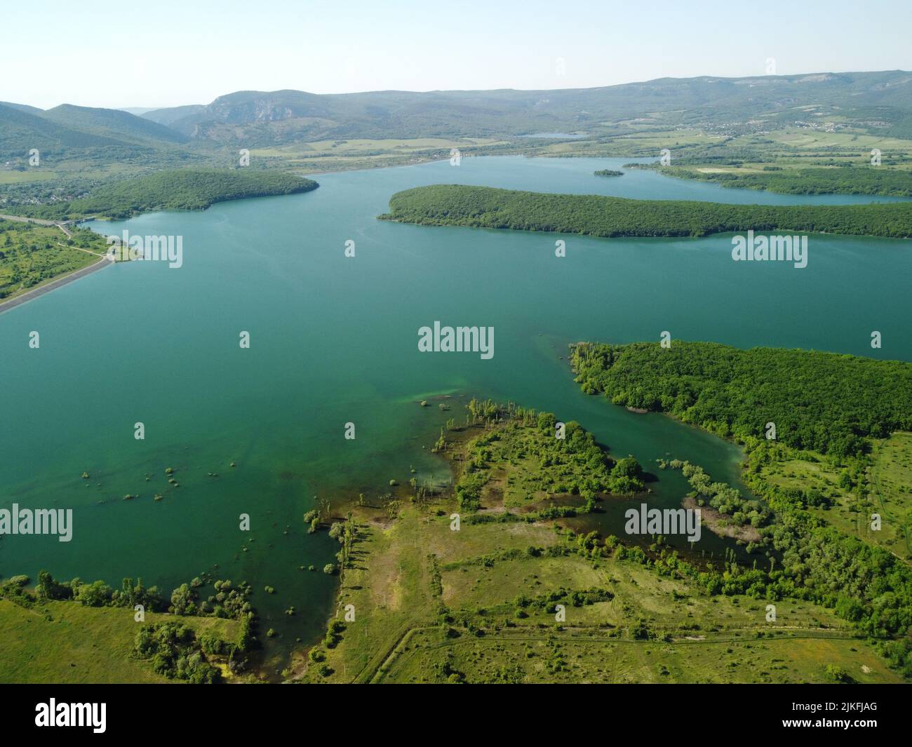Luftaufnahme des Wasserreservoirs im Bergtal, das mit einem grünen ...