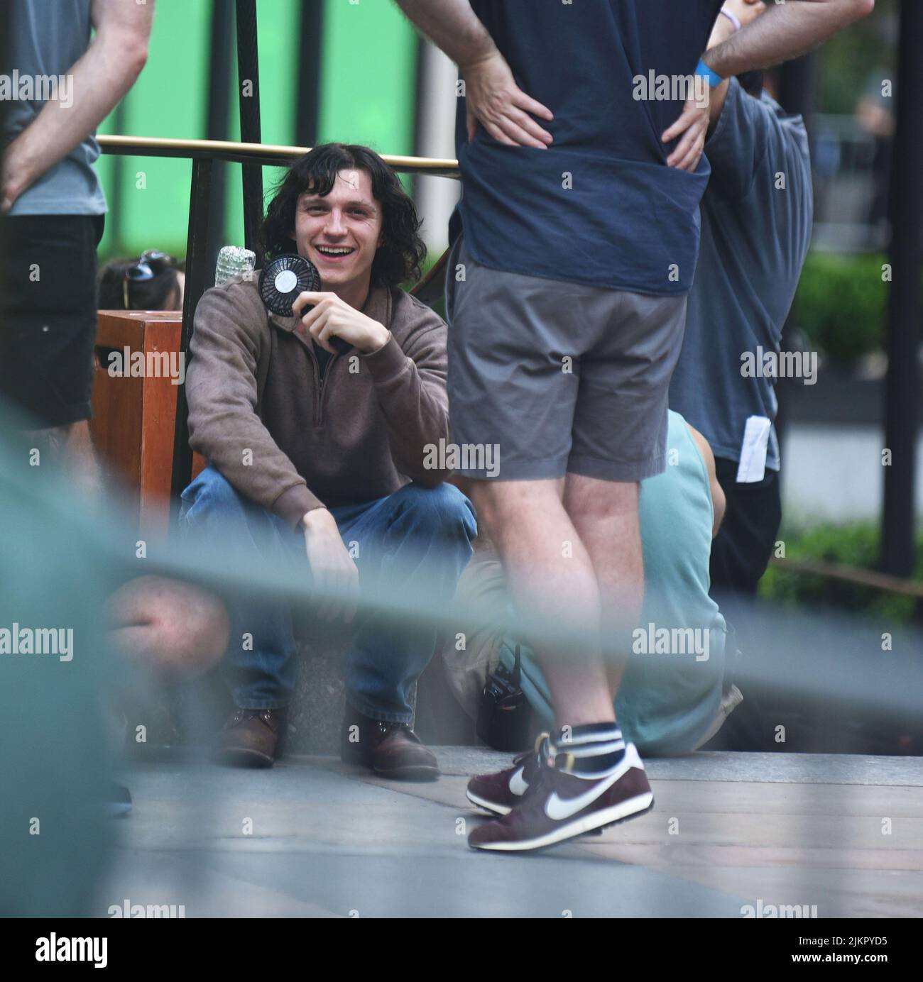 Tom Holland kühlt sich mit einem Fan ab, während er eine Pause von den ...