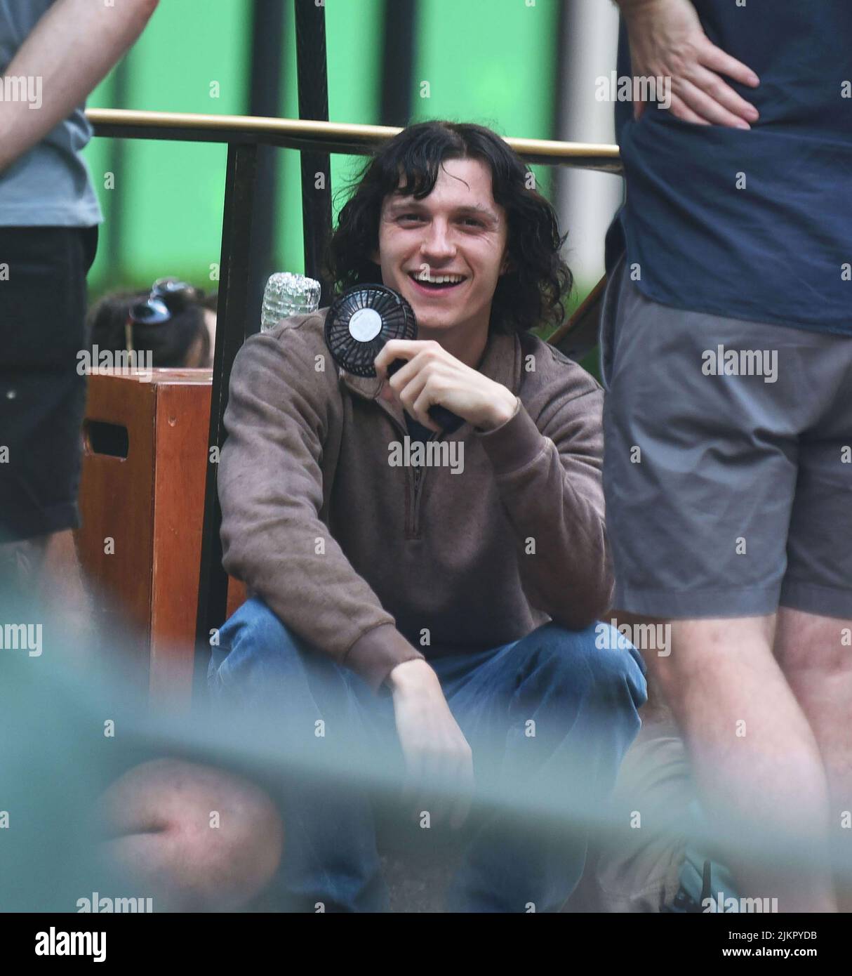 Tom Holland kühlt sich mit einem Fan ab, während er eine Pause von den ...