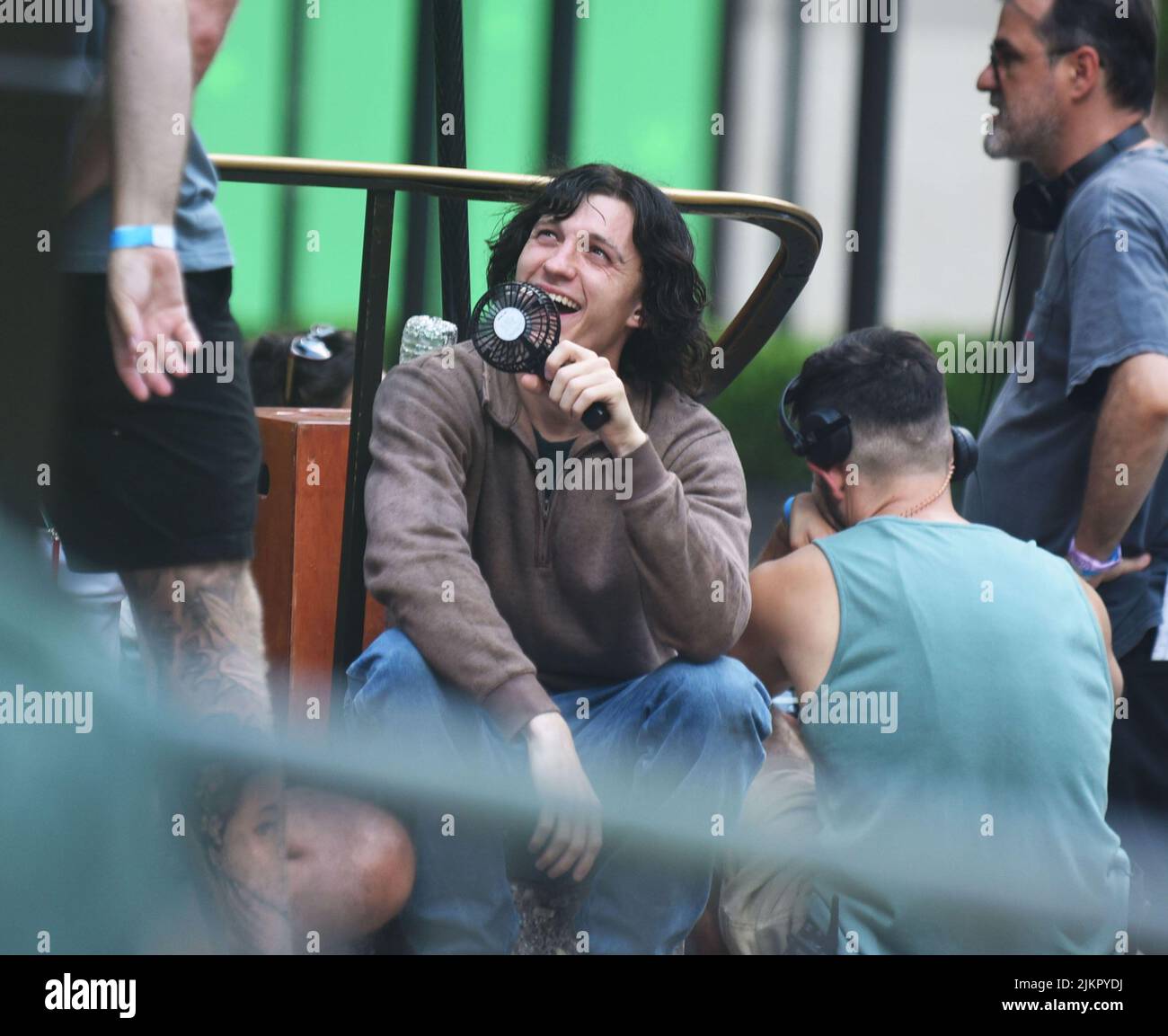 Tom Holland kühlt sich mit einem Fan ab, während er eine Pause von den ...