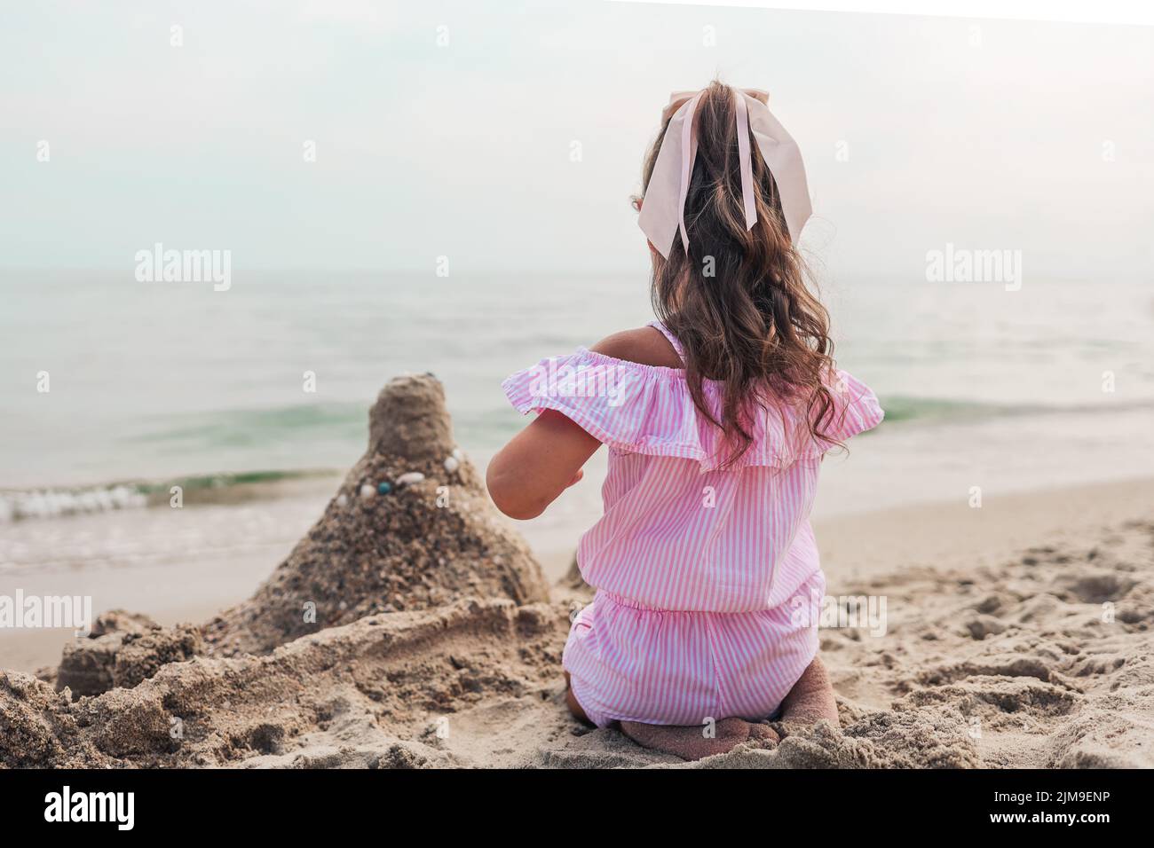 Ein Kind spielt an einem tropischen Strand. Das kleine Mädchen gräbt ...