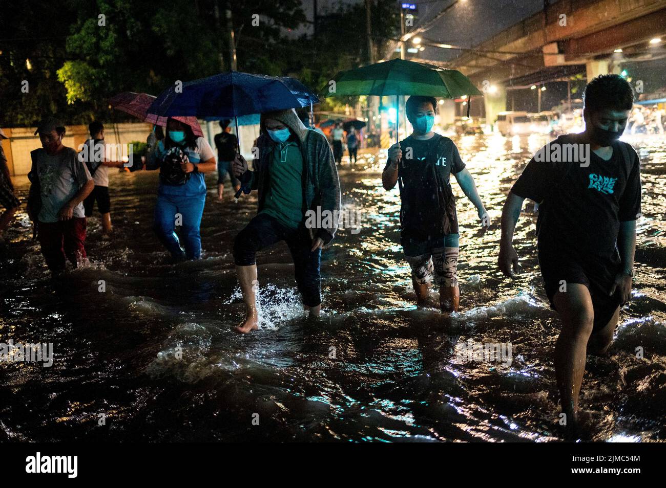 Menschen waten durch Hochwasser, das durch starke Regenfälle verursacht ...