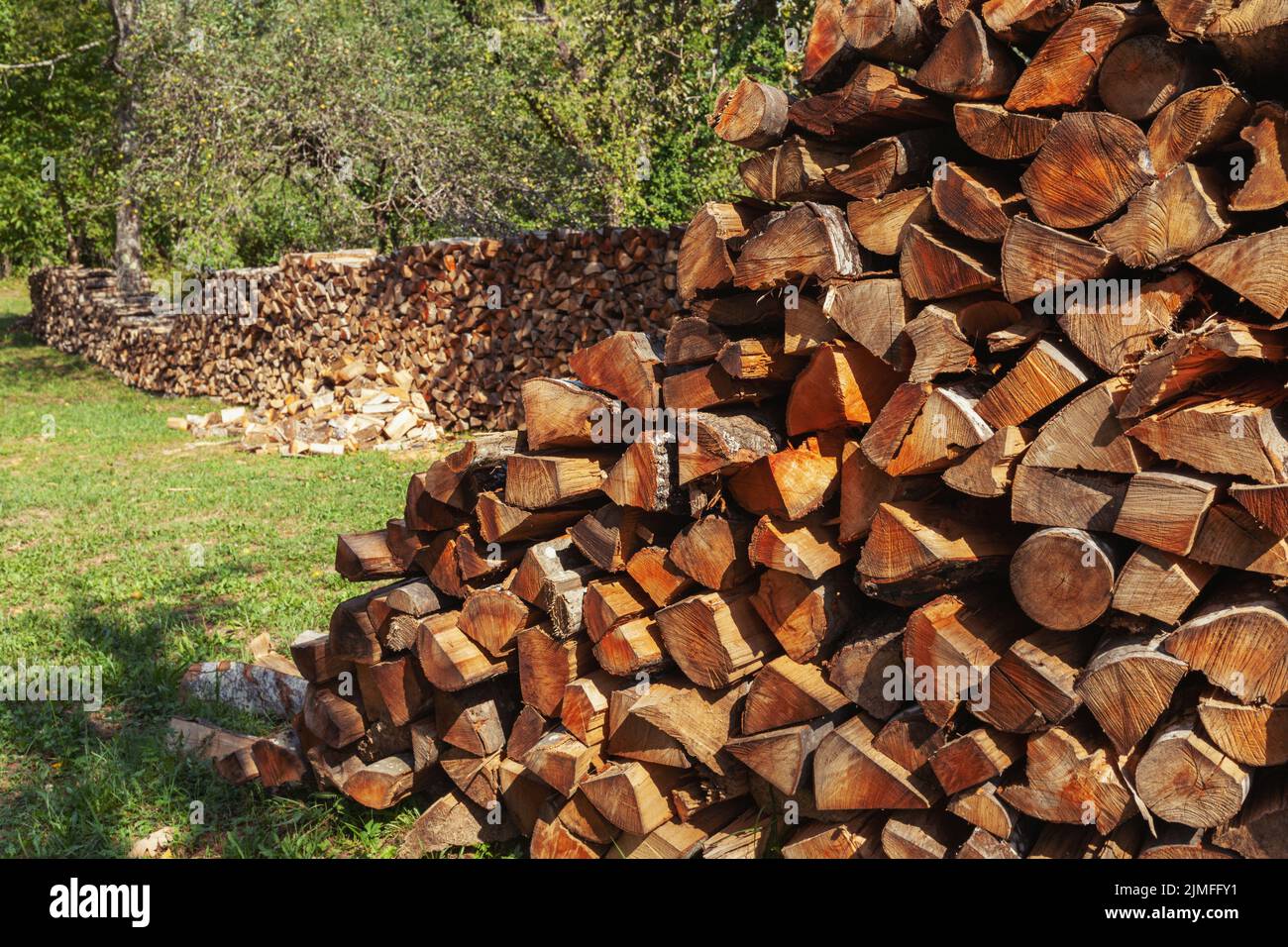 Großer Haufen Brennholz gehackt und ordentlich im Garten auf grünem ...