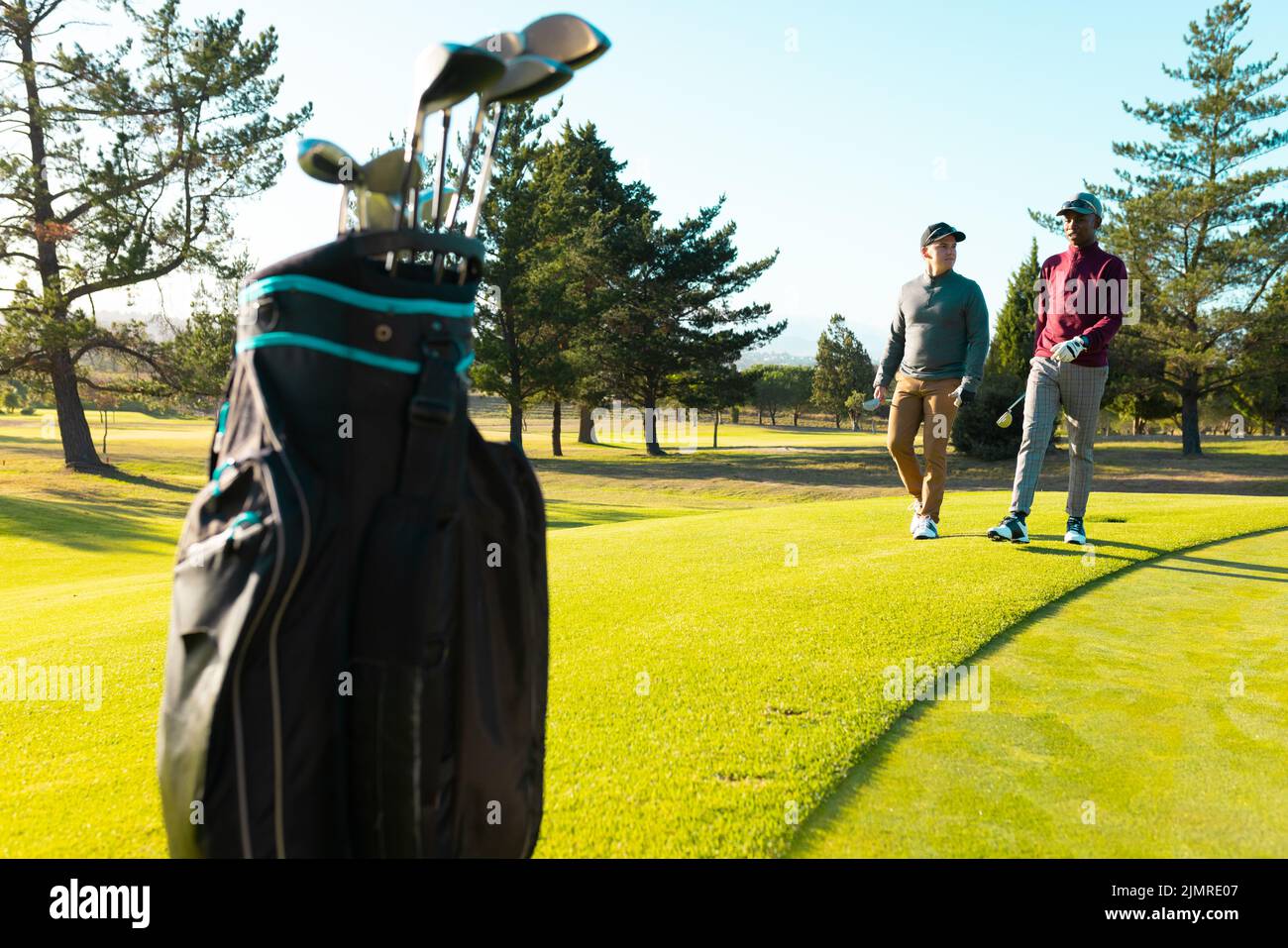 Golfschläger in der Tasche und multirassische junge männliche Freunde, die im Sommer auf dem ...