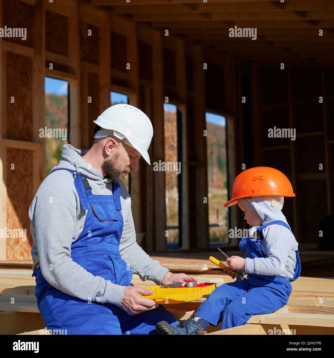 Vater mit Kleinkind Sohn Gebäude Holzrahmen Haus. Junge hilft seinem ...