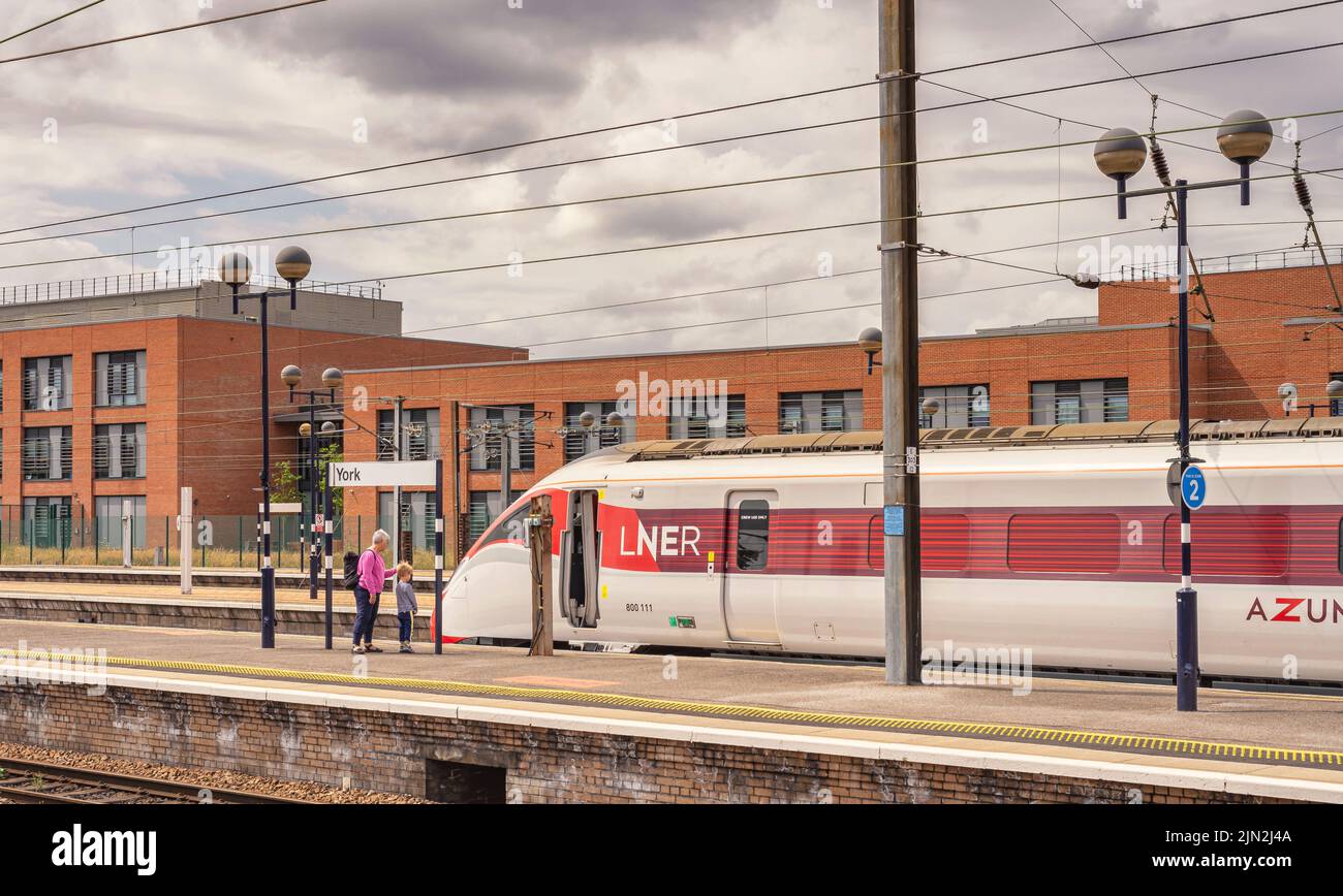 Ein moderner Zug steht am Bahnhofsplatz und ein Kind schaut in die ...
